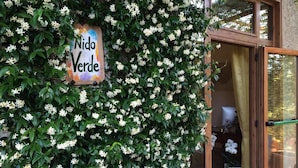 Entrada de um edifício com uma placa indicando 'Nido Verde' e um conjunto de sebe verdejante.