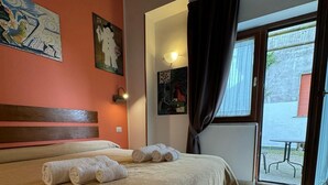 Quarto com cama, cabeceira de madeira, janela com cortinas e quadros nas paredes.