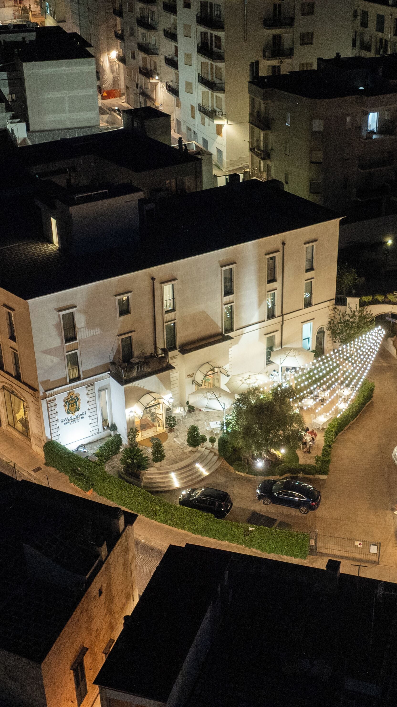 Um edifício com vários andares, um pátio, área de estar externa e estacionamento.