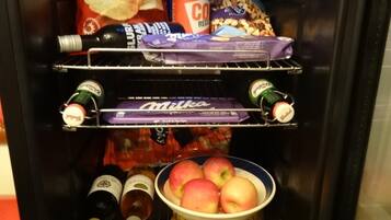 Um minibar com lanches, bebidas e uma taça de maçãs.