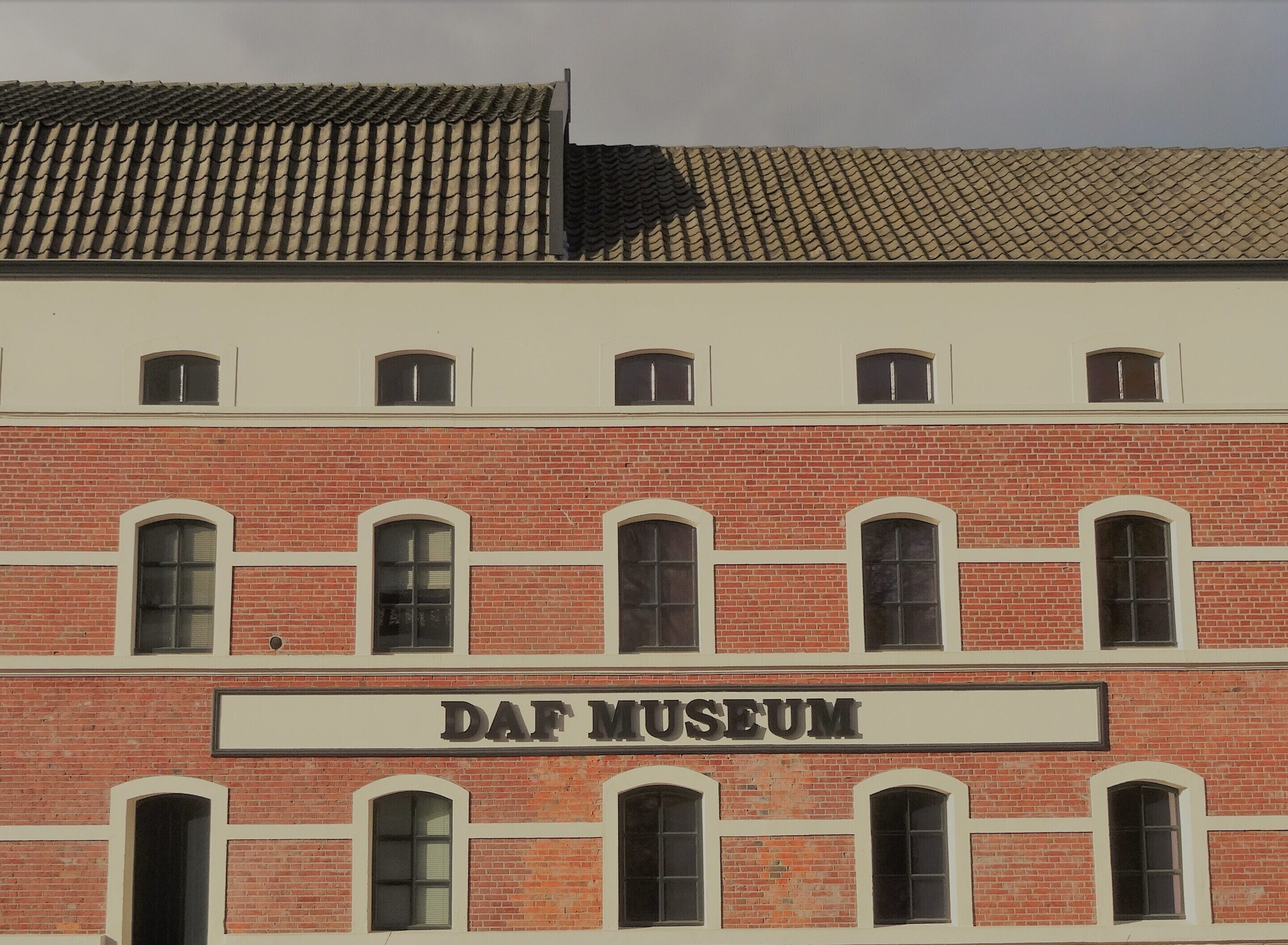 Um edifício com fachada de tijolos vermelhos e uma placa com a inscrição 'DAF MUSEUM'.