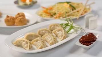 Uma mesa com diversos pratos, incluindo dumplings, um prato de macarrão e uma pequena tigela de molho.