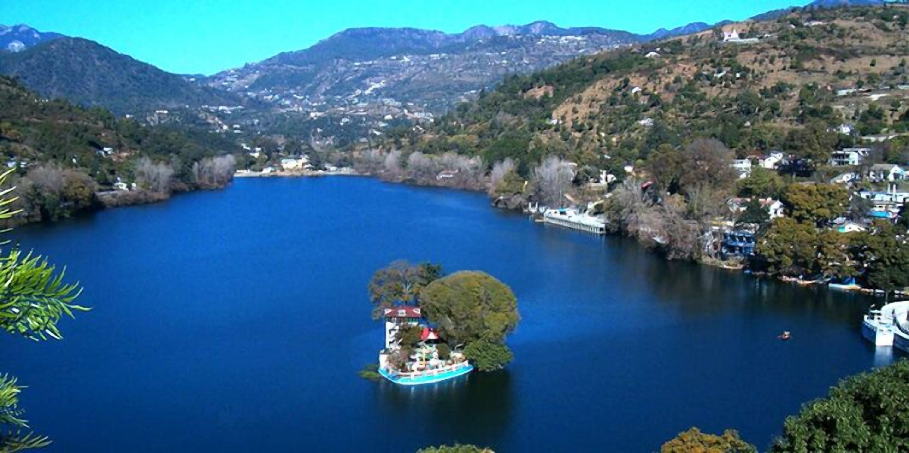 Um lago rodeado por colinas, com uma pequena ilha que apresenta um barco e um edifício.