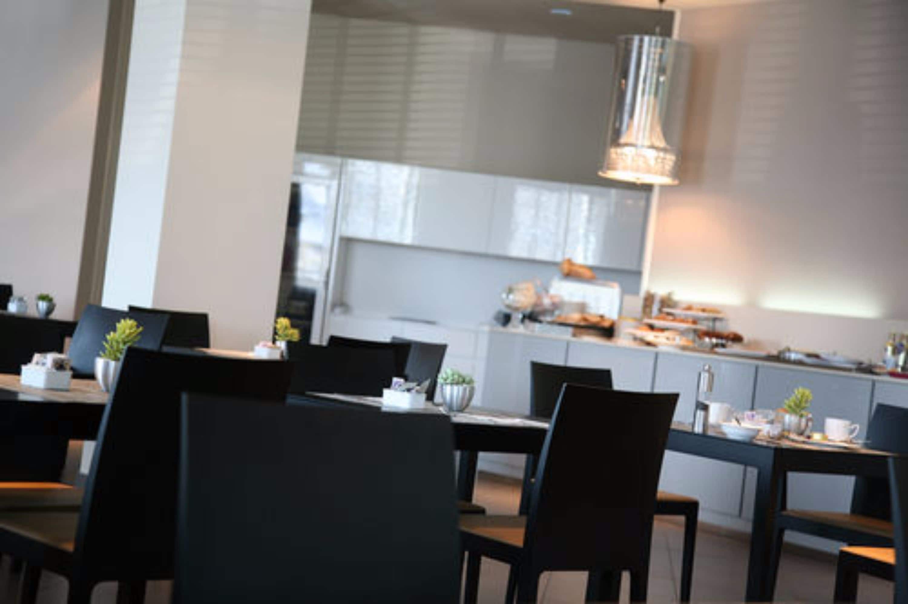 Uma área de jantar moderna com cadeiras pretas e uma mesa posta para dois.