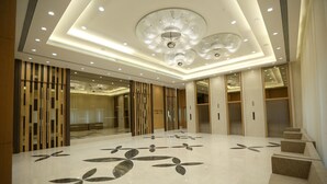 Um hall amplo com piso lustroso, luminárias modernas e um espaço para sentar.