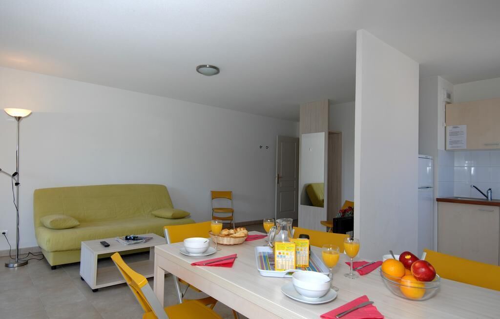 Espaço compacto com área de refeições, cozinha compacta e sofá verde.