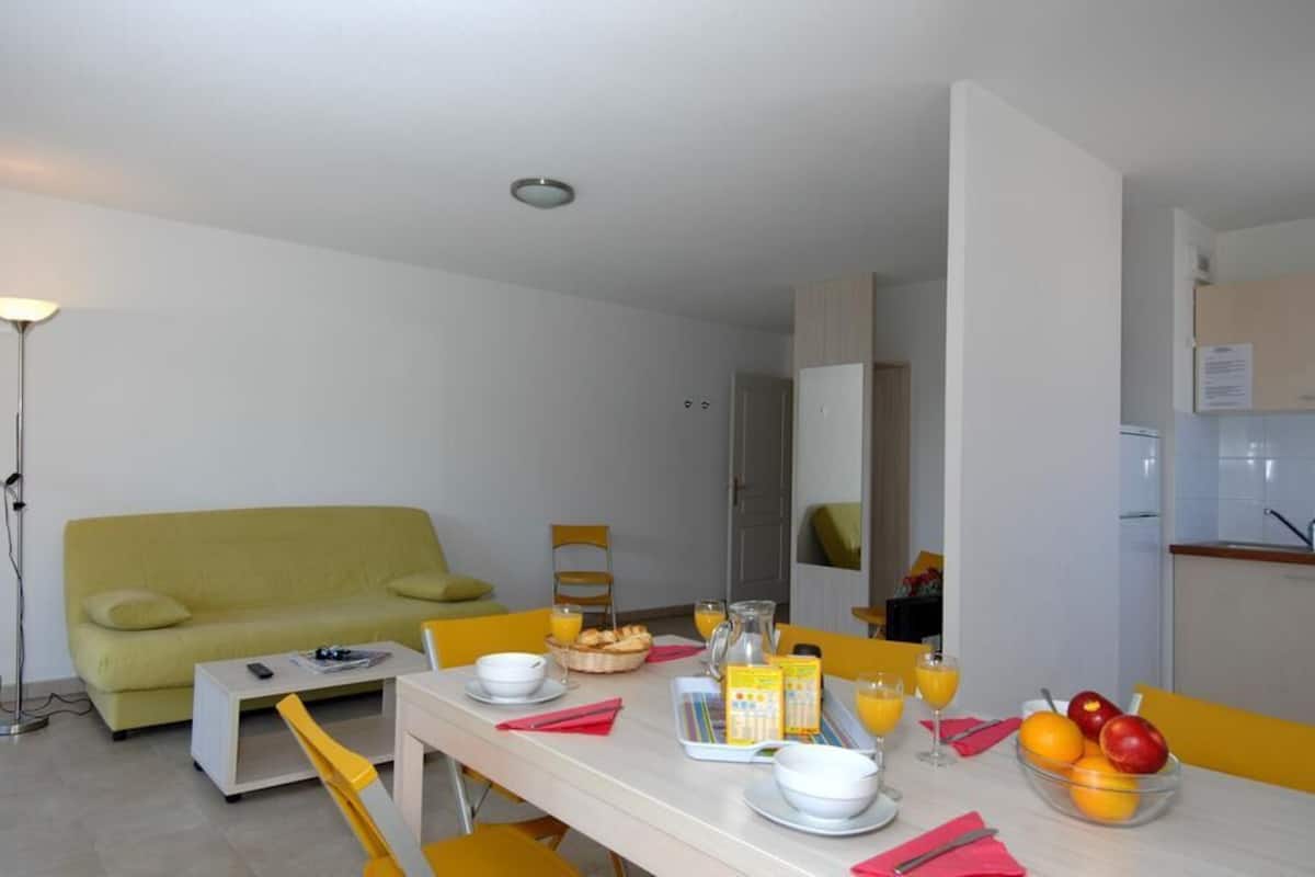 Espaço compacto com área de refeições, cozinha compacta e sofá verde.