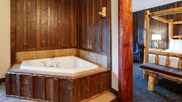 Um banheiro em estilo cabana de madeira, com uma banheira livre, um banco de madeira e uma cabeceira de madeira.