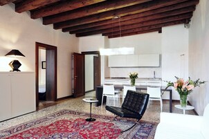 Um interior moderno com teto de madeira, área de jantar com cadeiras, um sofá e um tapete estampado.