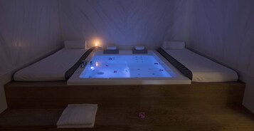 Um espaço de spa com hidromassagem, escadas de madeira e uma toalha no chão.