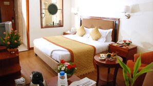 Quarto de hotel com cama, mesa de cabeceira, abajur e espelho na parede.