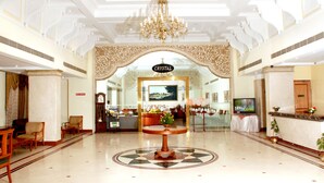 Um hall imponente com um candelabro, uma mesa de recepção e uma placa com a inscrição "CRYSTAL".
