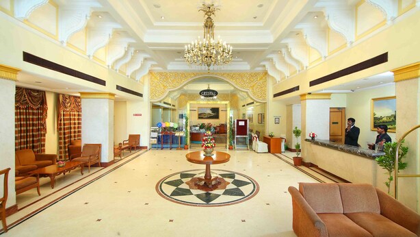Um hall amplo com uma fonte central, lustres elegantes e um balcão de recepção.