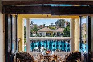 Varanda com vista para um bairro residencial, com uma mesa de frutas e duas cadeiras de vime.