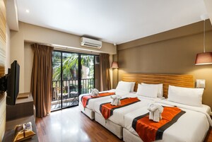 Quarto de hotel com duas camas, televisão e varanda com cortinas.