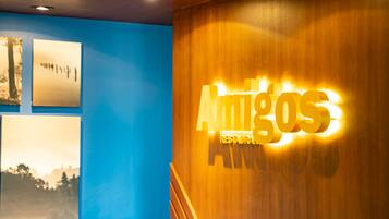 Pareda com um letreiro que diz "Amigos Restaurant" e um painel de madeira.