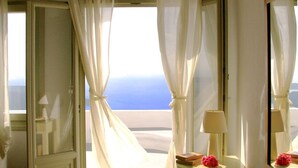 Quarto com vista para o oceano, uma cama, uma mesinha de cabeceira com abajur e um espelho.