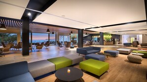 Uma área de estar ampla com diversas opções de assento, incluindo sofás e poltronas, uma mesa de centro e vista para o exterior.