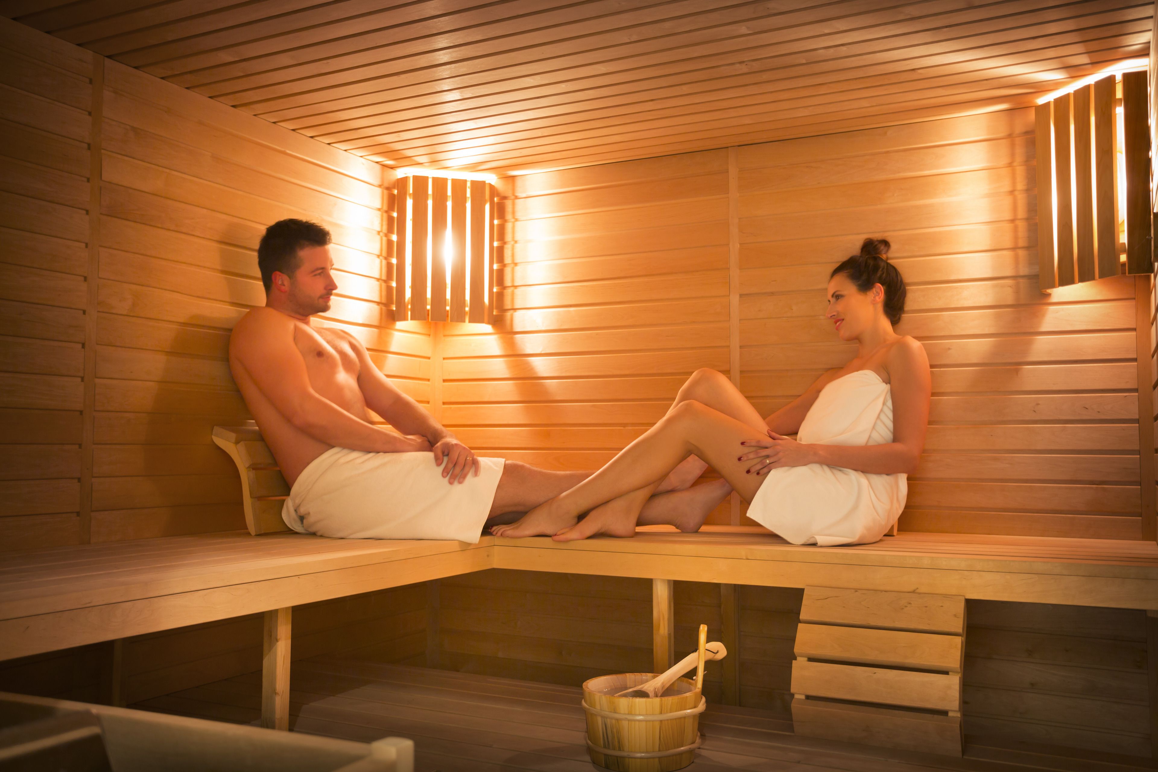 Uma sauna com bancos de madeira e um balde com uma escova.