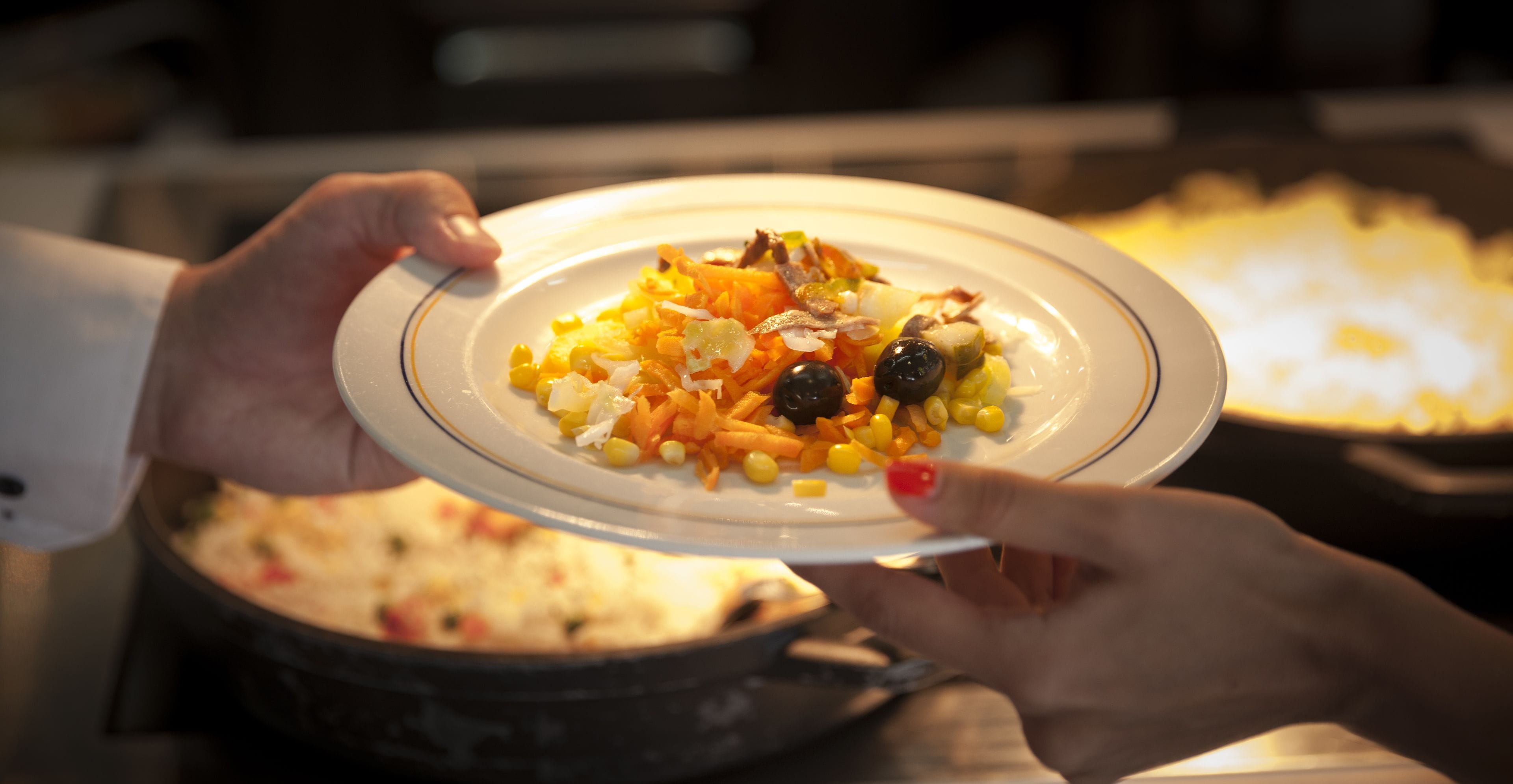 Uma pessoa segurando um prato com comida, possivelmente em um restaurante ou área de refeições.