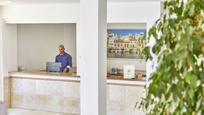 Um balcão de recepção com um homem atrás, um computador e um quadro com uma vista para a água.