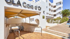 Um edifício com uma placa que diz "OLA Cala d'or" e uma área externa coberta com degraus que o levam até ele.