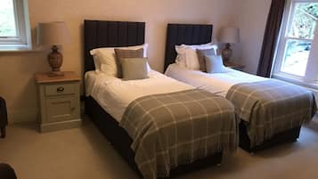 Quarto duplo com duas camas, cada uma com cabeceira, mesas de cabeceira, abajures e janela com cortinas.
