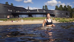 Uma mulher em uma piscina com um edifício moderno ao fundo.