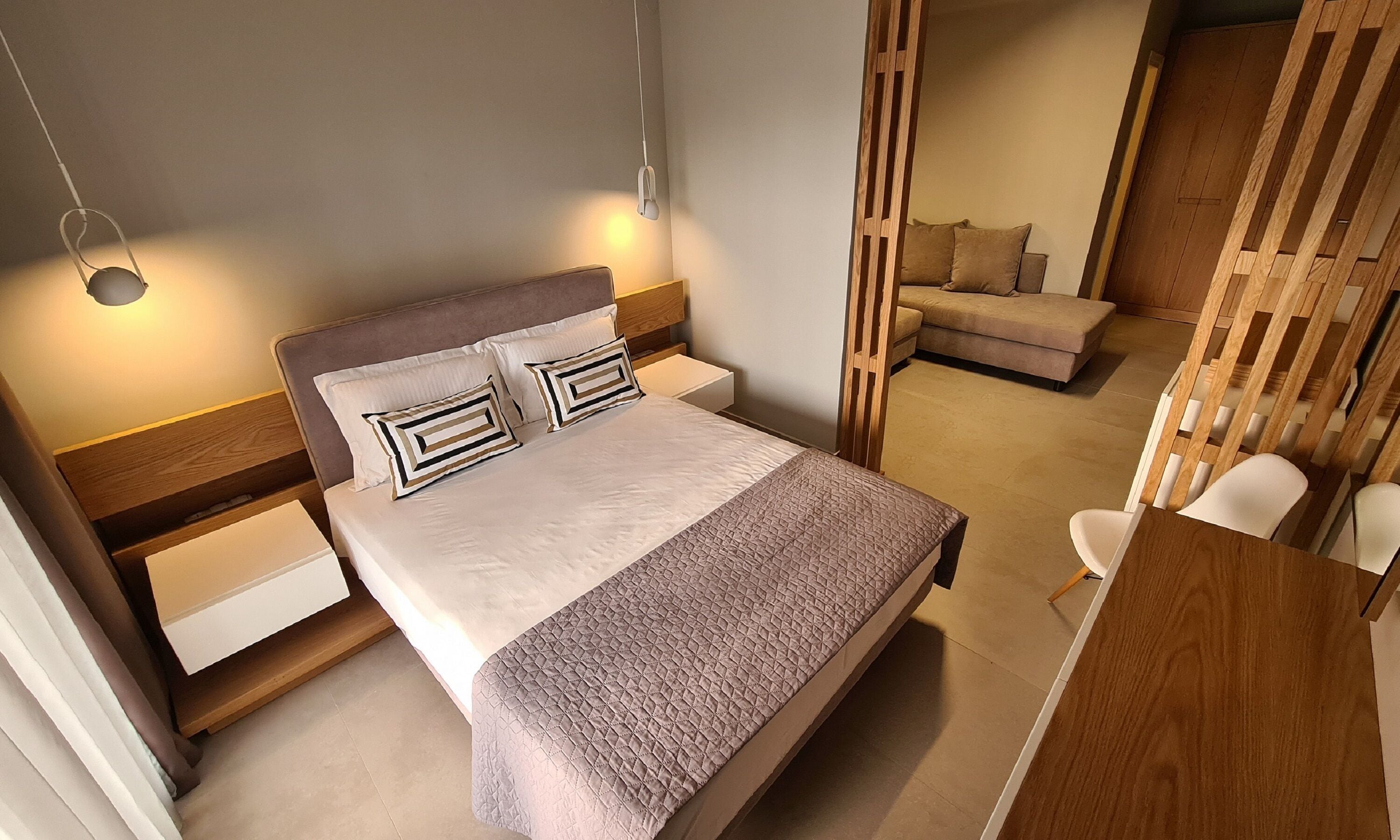 Quarto moderno com uma cama grande, mesas de cabeceira, escrivaninha e um sofá.