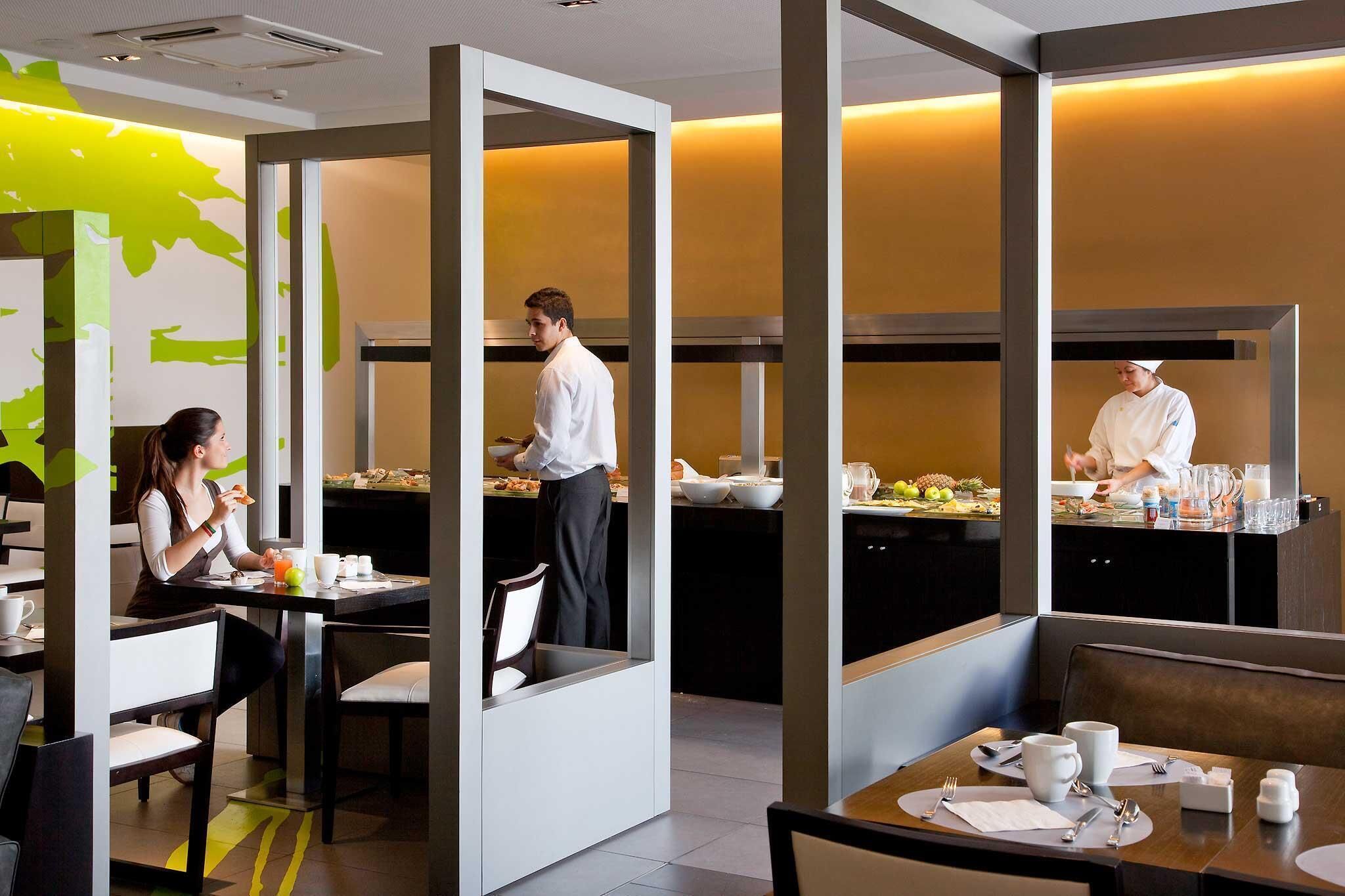 Uma área de refeições moderna, com assentos divididos e cozinha à vista.