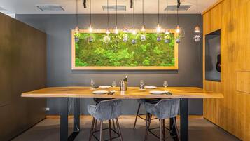 Uma sala de jantar moderna com uma mesa comprida, duas cadeiras cinzentas e um lustre.