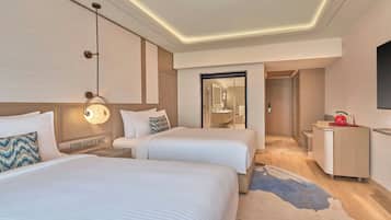Quarto de hotel com duas camas, banheiro e cozinha compacta.
