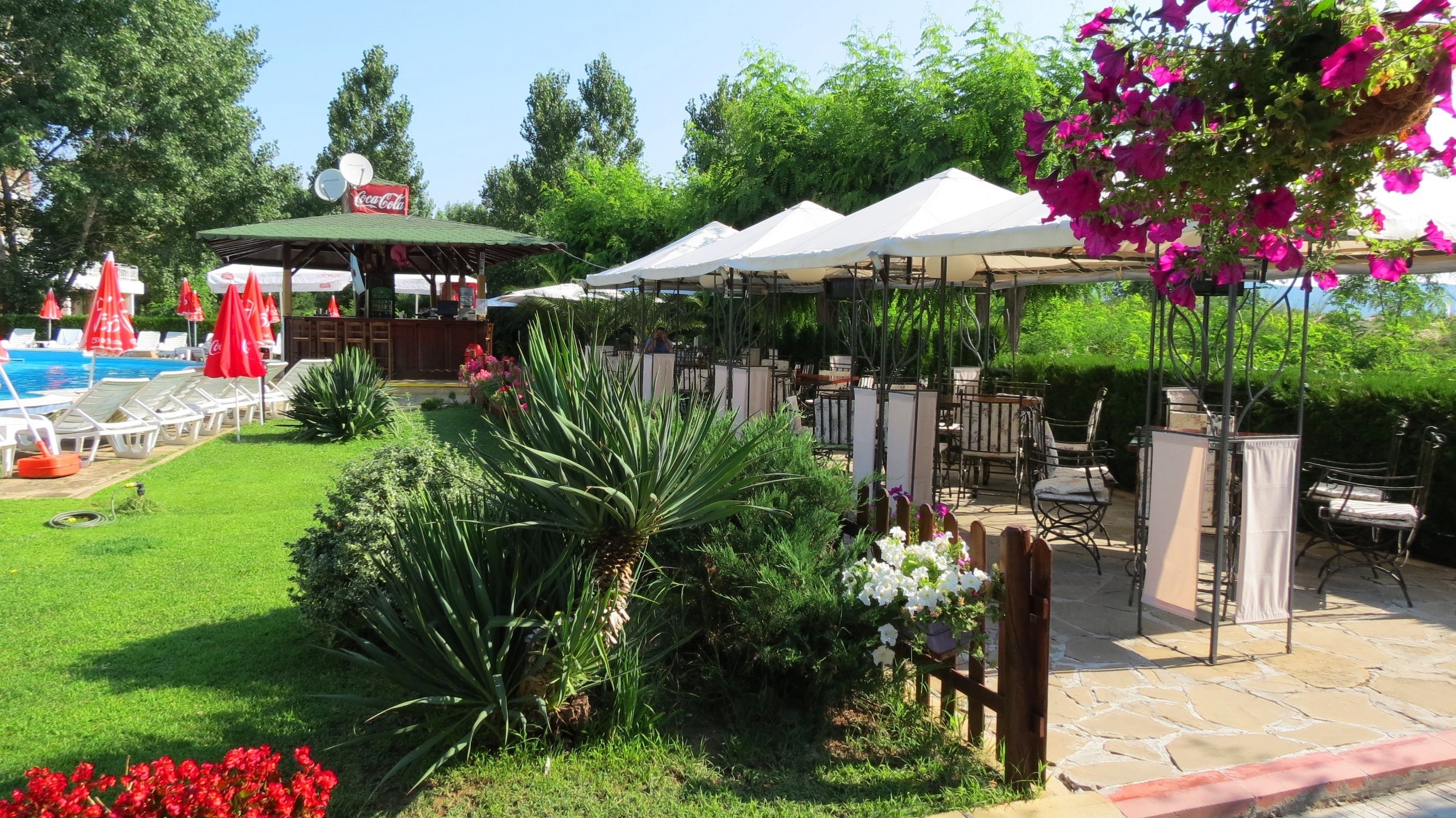 Uma área de jardim com mobiliário de exterior, uma piscina e um anúncio da Coca-Cola.