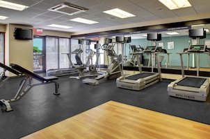 Centro de fitness do hotel com esteiras, elípticos e um banco.