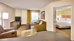 Quarto de hotel com cama, televisão, escrivaninha e sofá.