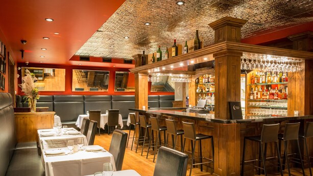 Restaurante com área de bar, cabines e balcão com banquetas.