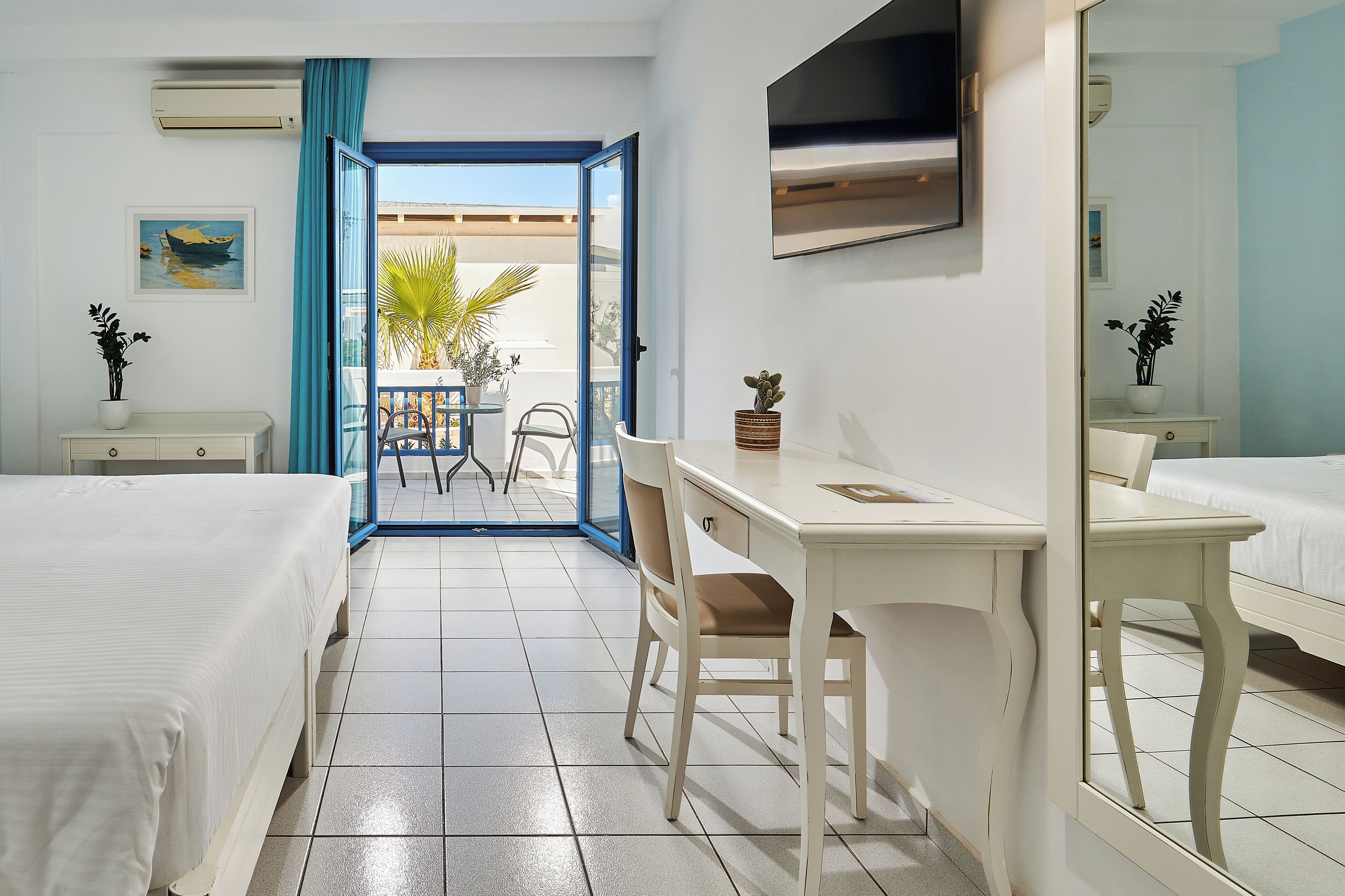 Quarto de hotel com cama, escrivaninha, cadeira e varanda com vista.