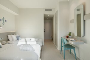 Quarto de hotel com duas camas, uma escrivaninha, uma cadeira, uma pia e um espelho.