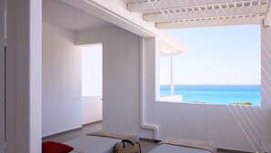 Quarto com duas camas, vista para o mar e teto branco.