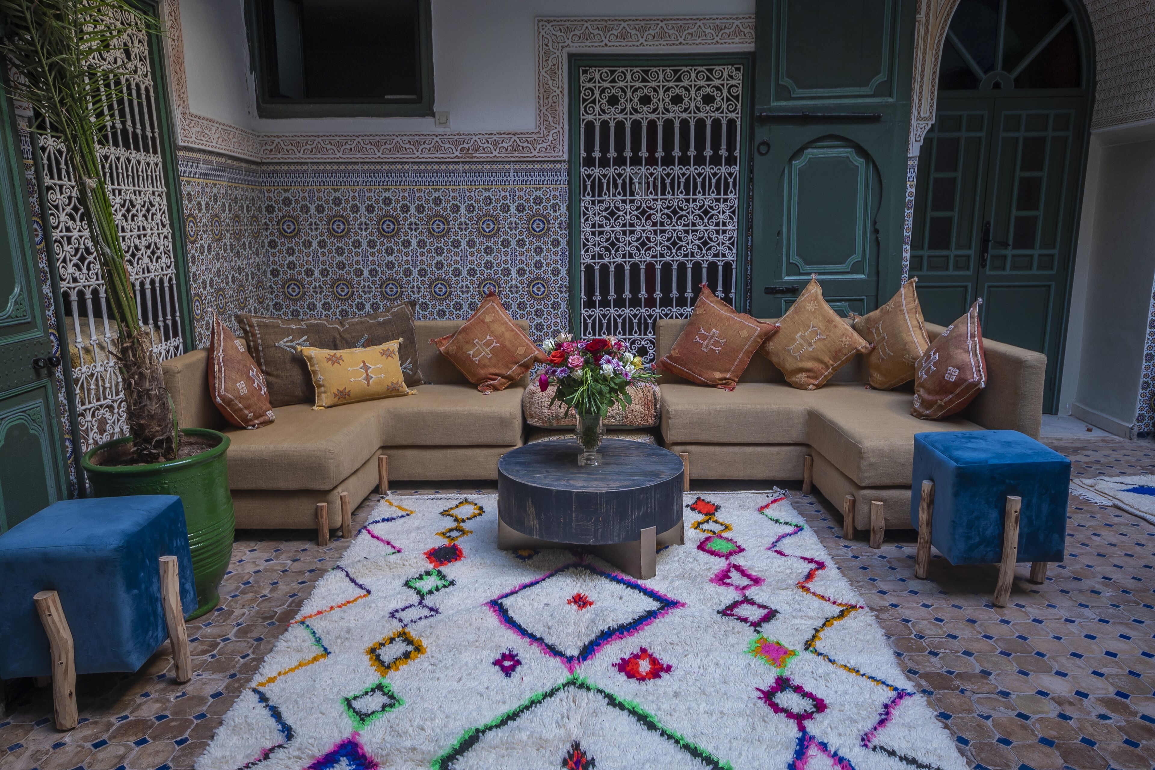 Uma área de estar aconchegante com sofá, almofadas, mesa de centro e tapete estampado.