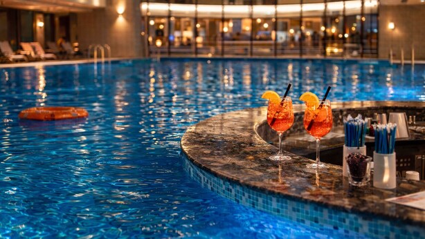 Piscina com espreguiçadeiras e um bar com bebidas.