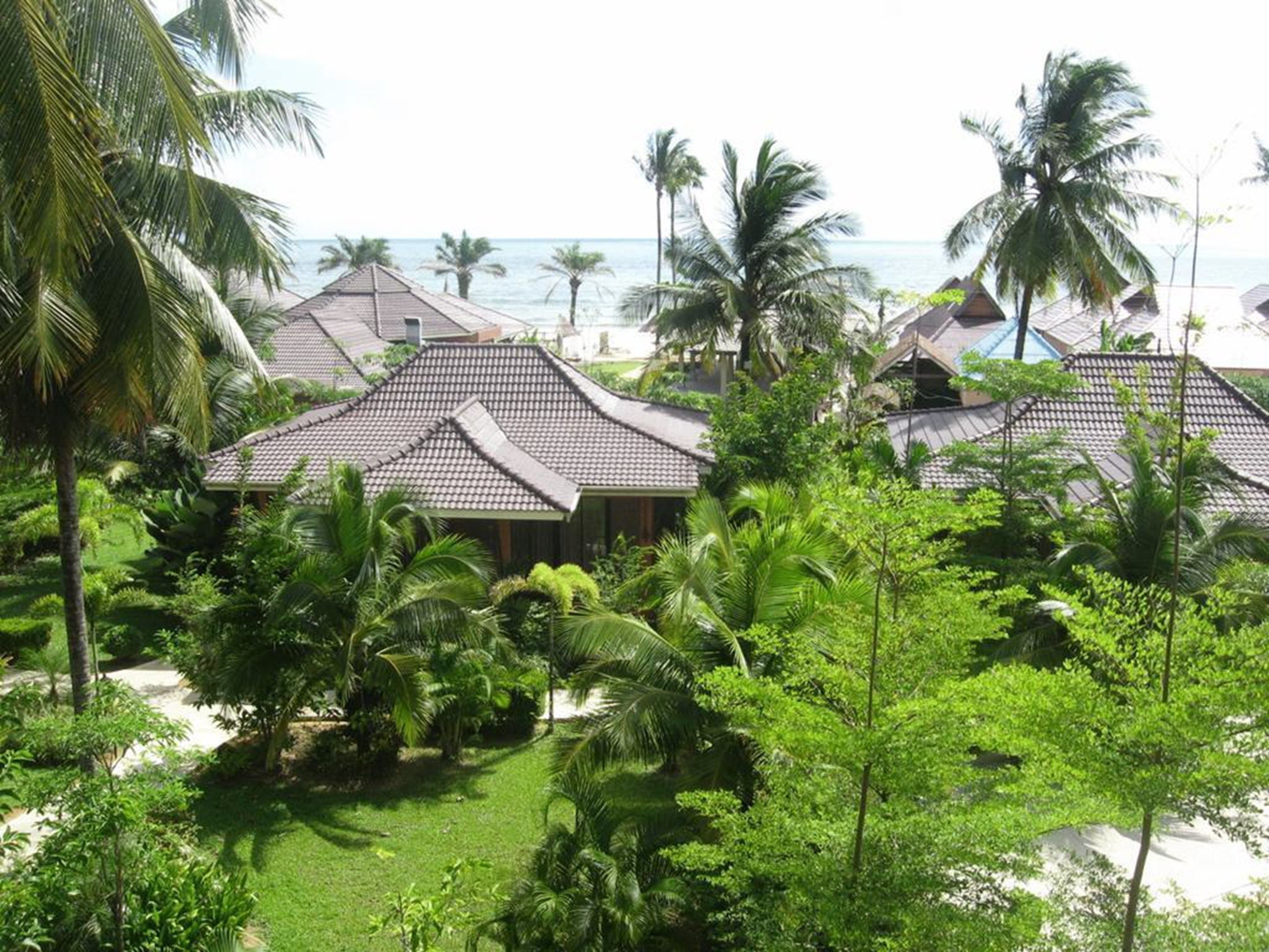 Resort com vários edifícios, vegetação exuberante e vista para o oceano.