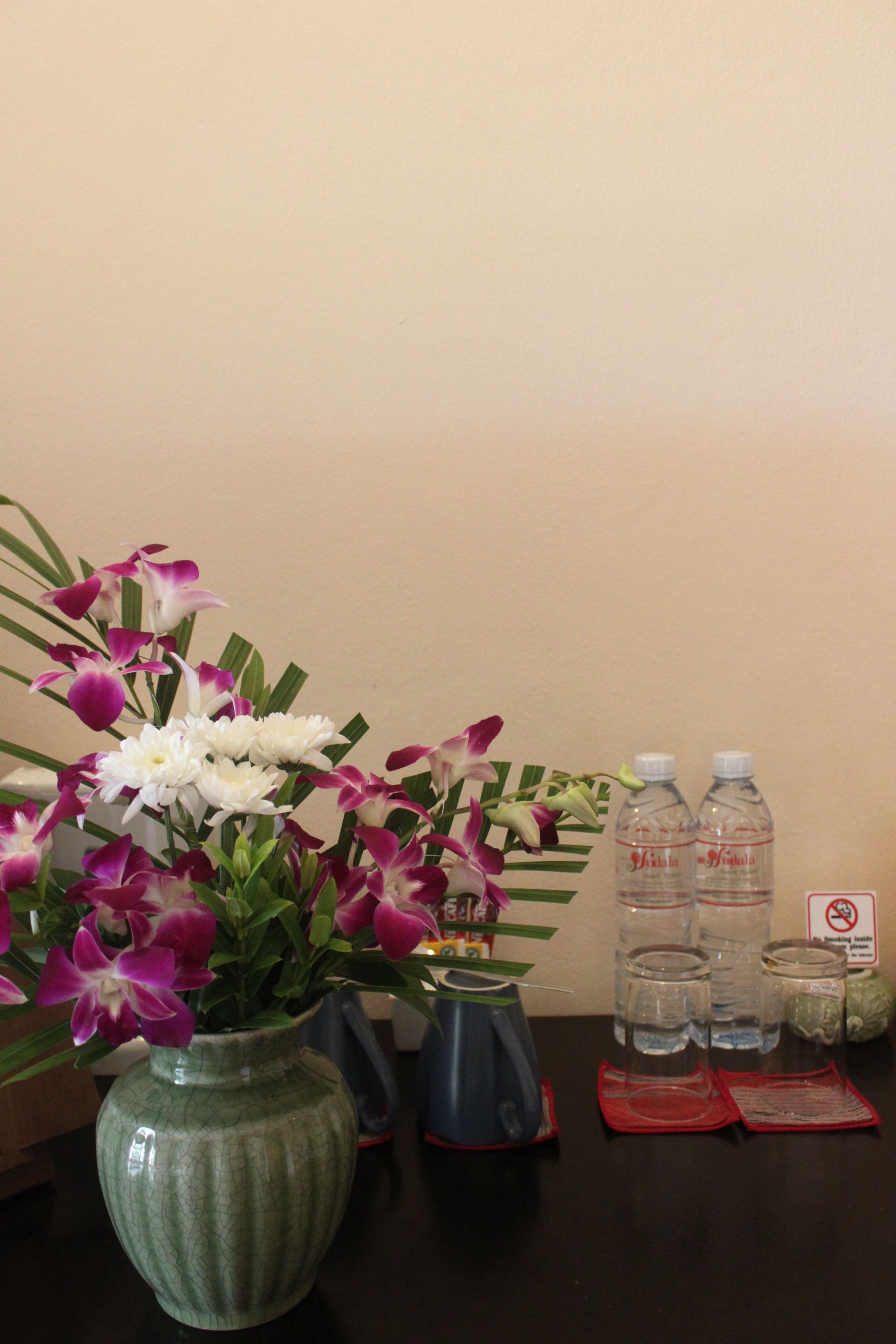 Uma mesa com um vaso de flores, garrafas de água e um aviso de proibido fumar.
