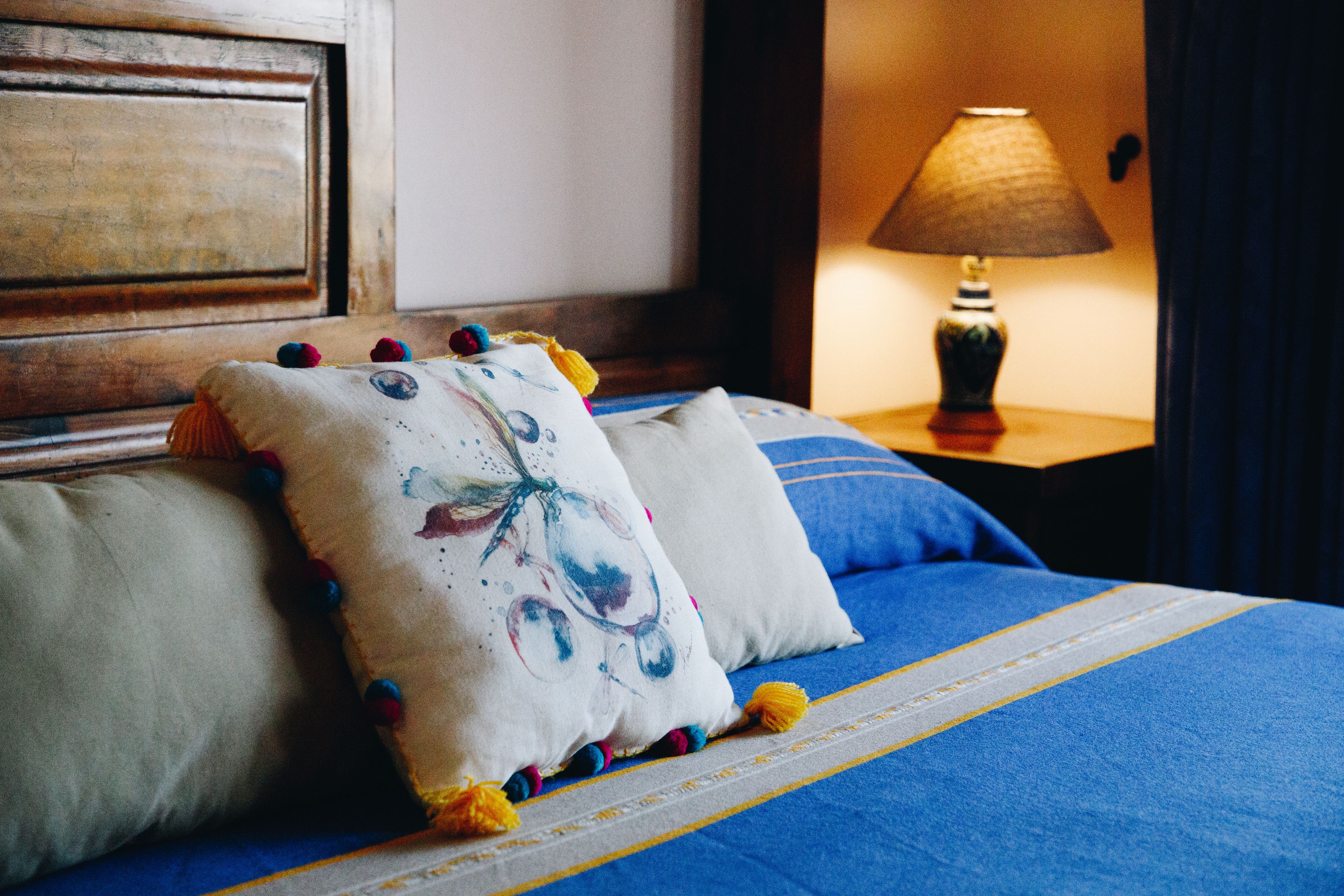 Cama bem arrumada com roupa de cama azul e almofadas decorativas.