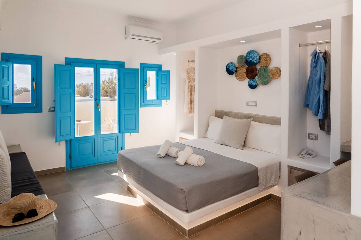 Quarto com cama, guarda-roupa, banheiro e varanda.