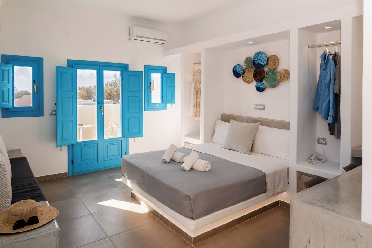Quarto com cama, guarda-roupa, banheiro e varanda.
