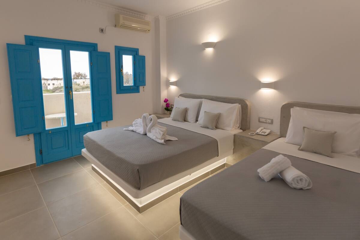 Quarto de hotel com duas camas, banheiro e vista para o mar.