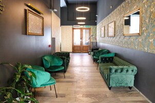 Um corredor com assentos estofados em verde, piso de madeira e obras de arte emolduradas nas paredes.