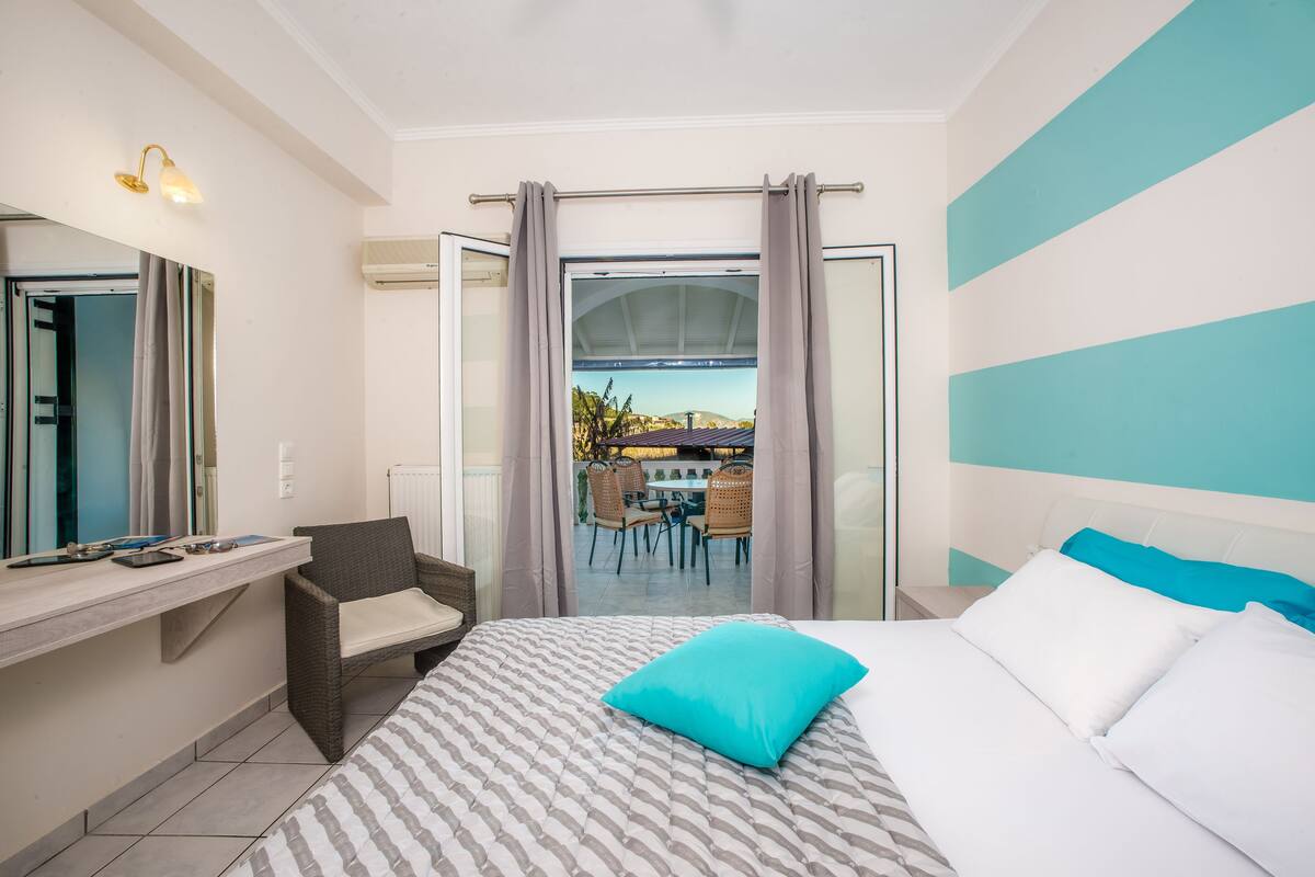 Quarto de hotel com cama, poltrona, escrivaninha e vista para o exterior.