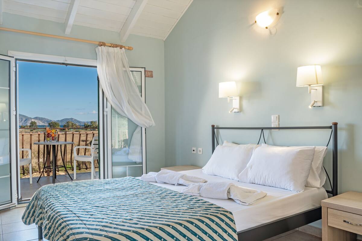 Um quarto com uma cama, uma mesinha de cabeceira, uma janela com vista para o exterior e uma cortina.